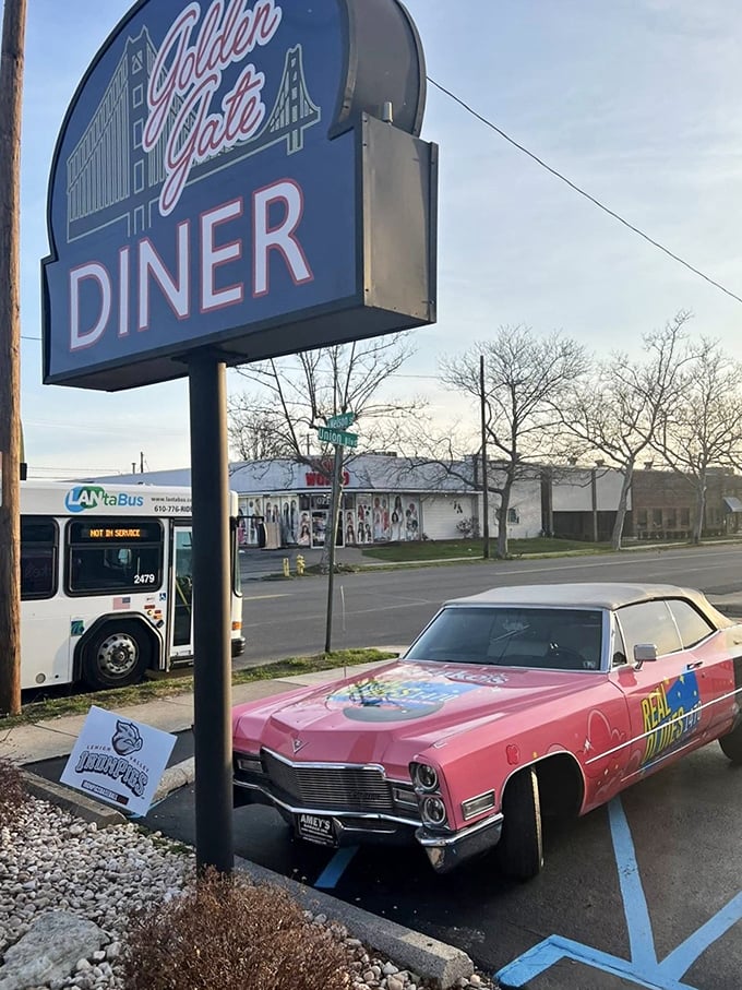 That vintage pink Cadillac parked beneath the sign isn't just transportation—it's a time-traveling chariot waiting to whisk you to an era when diners ruled American cuisine.