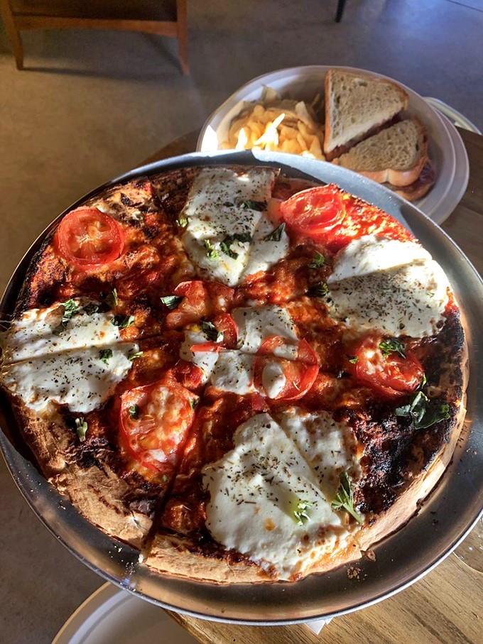 This isn't just pizza—it's a crispy canvas of melted cheese, garden-fresh tomatoes, and herbs that pairs perfectly with whatever's in your glass.