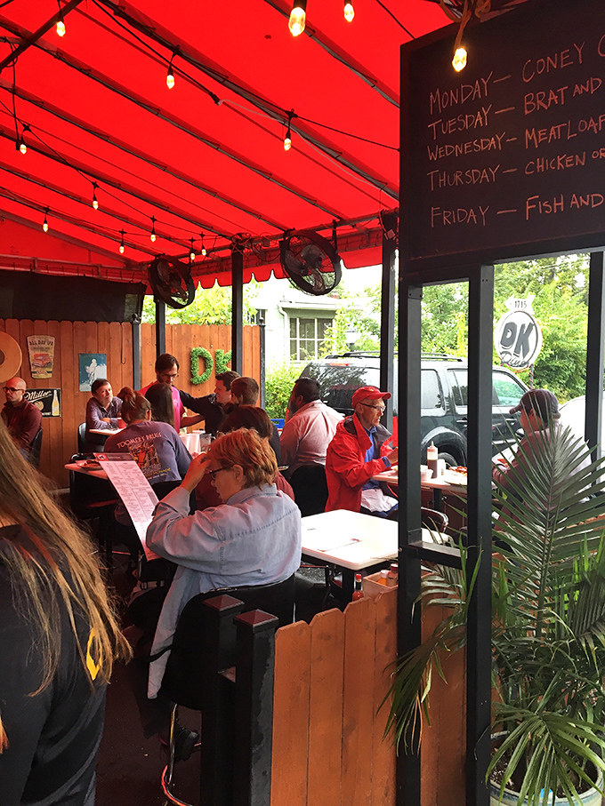 The outdoor seating area glows with a welcoming red hue, while the daily specials board promises comfort food that makes every day feel like Friday.