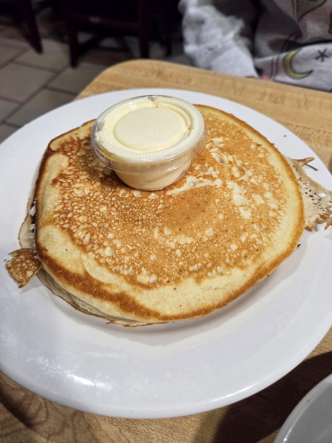 A pancake so perfectly golden it deserves its own Instagram account. That butter cup isn't a garnish—it's an essential life force.