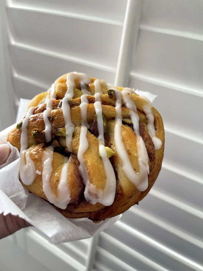 A pistachio cinnamon roll that's dressed better than most people at fashion week. Those vanilla drizzles aren't just decoration—they're edible exclamation points.