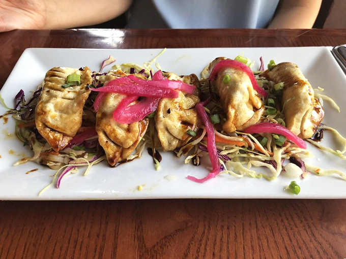 These pot stickers aren't just folded—they're lovingly crimped into perfect pockets of flavor, resting on a bed of slaw that adds crunch and color.