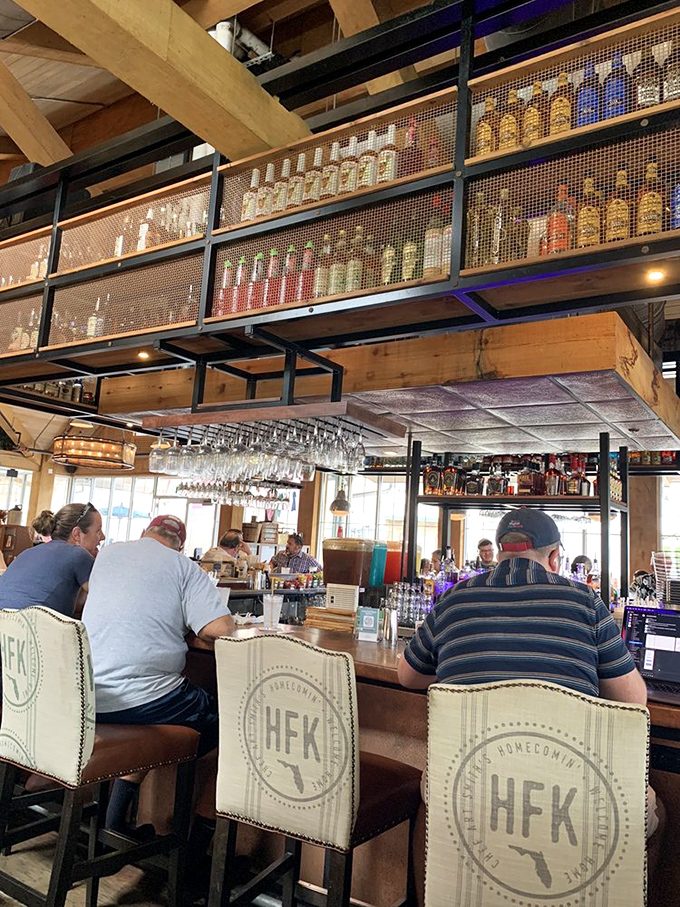The bar's impressive moonshine collection displayed like liquid treasure. Those chairs emblazoned with "HFK" aren't just seating—they're Florida pride in furniture form.
