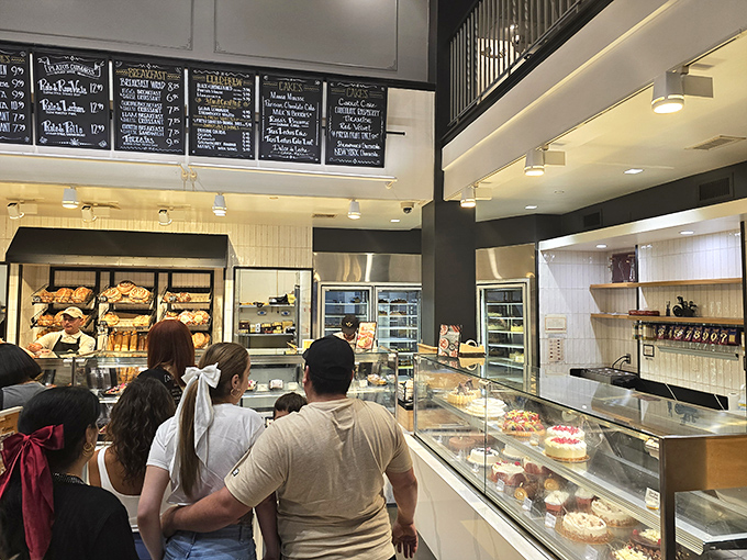 The display case pilgrimage—where customers line up for their turn at the glass altar of pastry perfection, eyes wide with sweet anticipation.