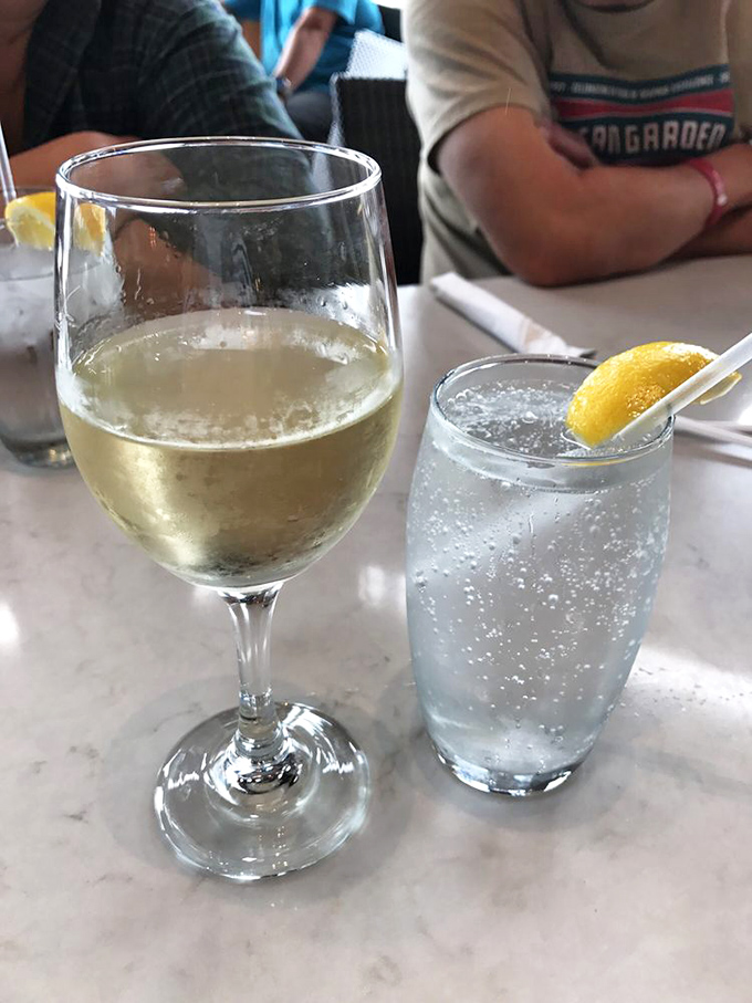A crisp glass of white wine alongside sparkling water—because proper hydration is important when embarking on a serious seafood expedition.
