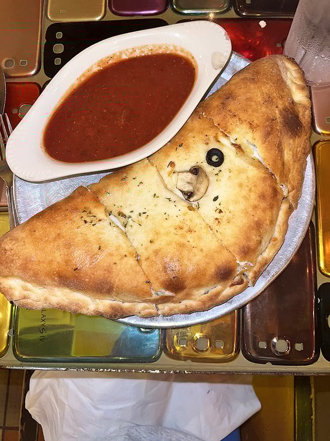 This calzone isn't just folded pizza – it's a self-contained treasure chest where X marks the spot with an olive and the gold is melted cheese.
