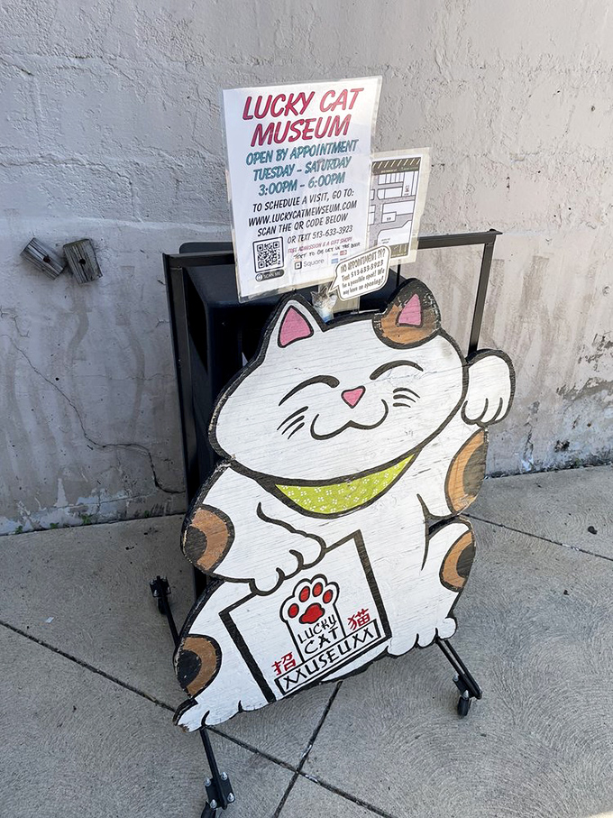 The museum's outdoor signage features appointment hours and a wooden cat cutout that serves as the perfect ambassador for this quirky cultural institution.