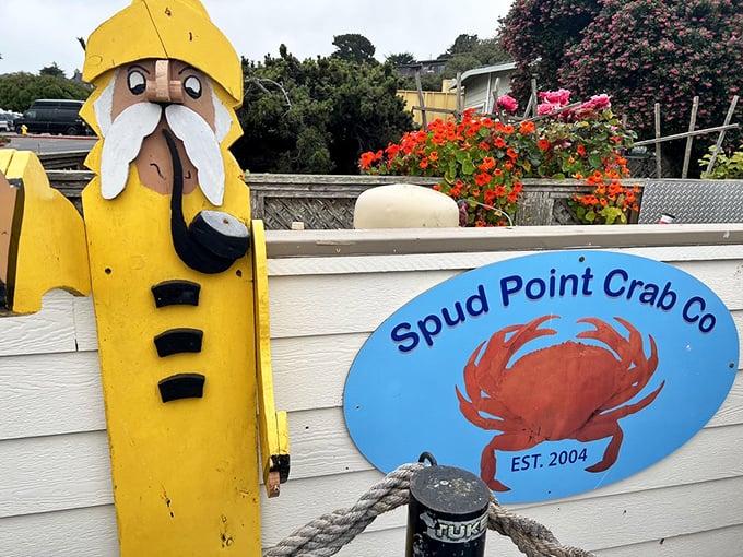 The whimsical sailor statue stands guard by the Spud Point sign – a quirky sentinel welcoming seafood pilgrims to chowder paradise.