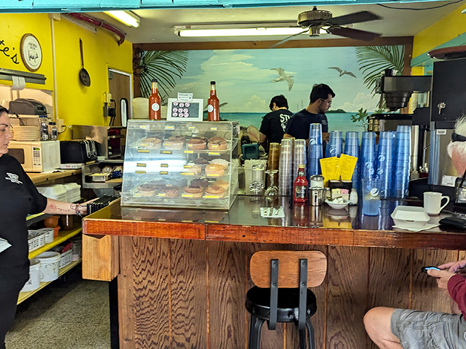 Behind the counter, where breakfast magic happens – complete with a beach mural that reminds you exactly where you are in this delicious world.