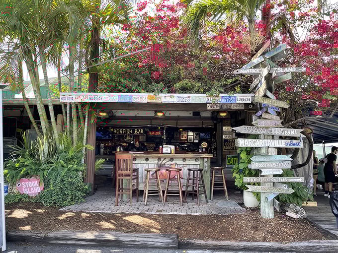 The ultimate tiki hideaway! Hogfish Bar's jungle-like entrance promises cold drinks and seafood treasures beneath those colorful directional signs.