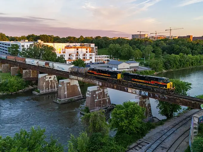 A train rumbles over the Iowa River in Iowa City, where affordable living meets college-town charm. Retirement dollars stretch further with these scenic views!