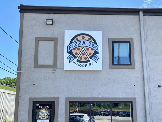 That bold "WOODFIRE" sign isn't just decoration—it's a promise of pizza magic happening inside those brick ovens.
