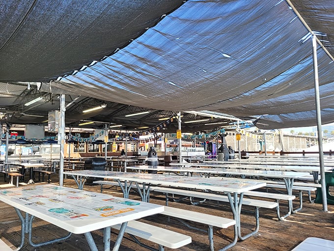 Picnic tables stretch as far as the eye can see under blue tarps, creating the perfect casual setting for the seafood feast of your dreams.