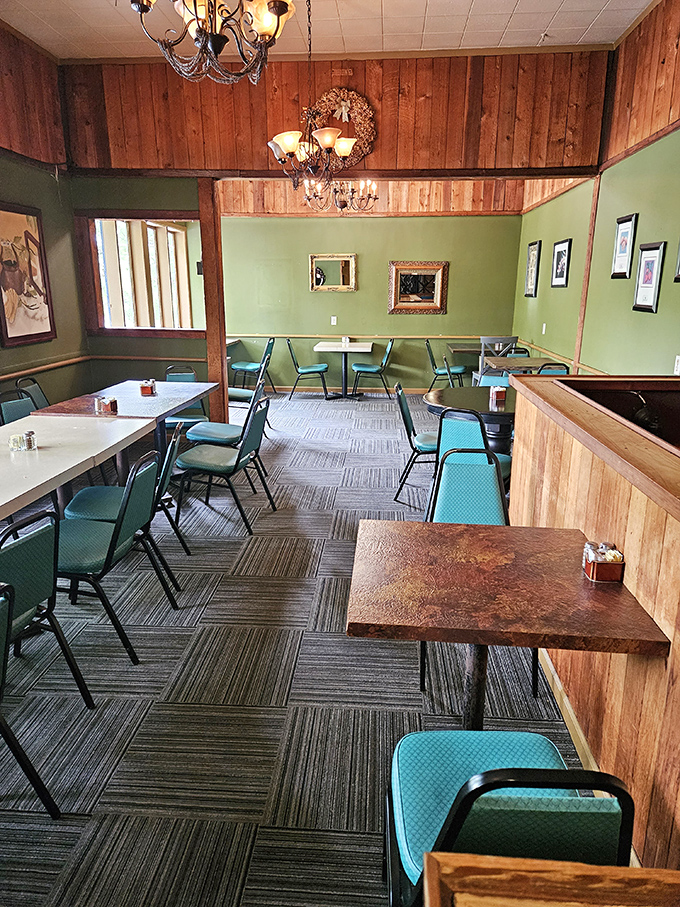Wooden paneling meets sage green walls in this cozy dining room where chandeliers cast a warm glow over conversations and coffee cups.