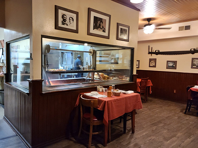 Step inside and time stands still—wood paneling, red tablecloths, and that window to culinary paradise where meat meets fire.