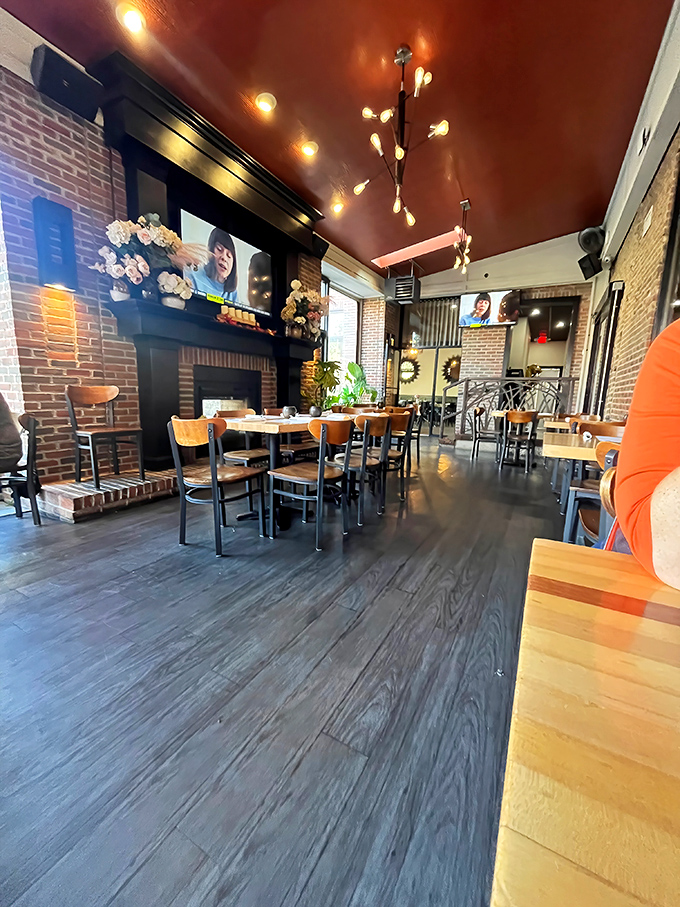 Exposed brick walls meet warm wood tones under a rich copper ceiling—like dining in a cozy jewelry box designed by someone with actual taste