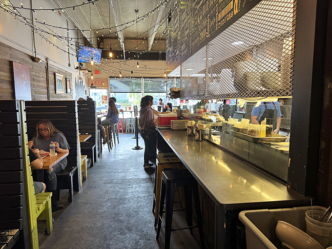Inside, string lights create a twinkling canopy above diners while the open kitchen promises transparency in both design and culinary philosophy.