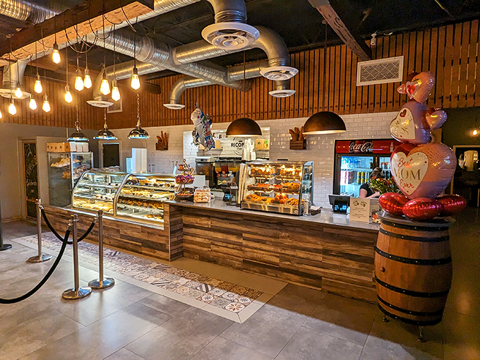 Edison bulbs cast a warm glow over wooden accents and subway tile, creating an atmosphere where industrial chic meets comfort – like your coolest friend's kitchen, but with better pastries.