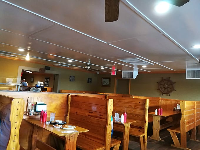 Nautical charm meets down-home comfort in these wooden booths. The ship's wheel on the wall isn't just decoration—it's steering you toward flavor paradise.
