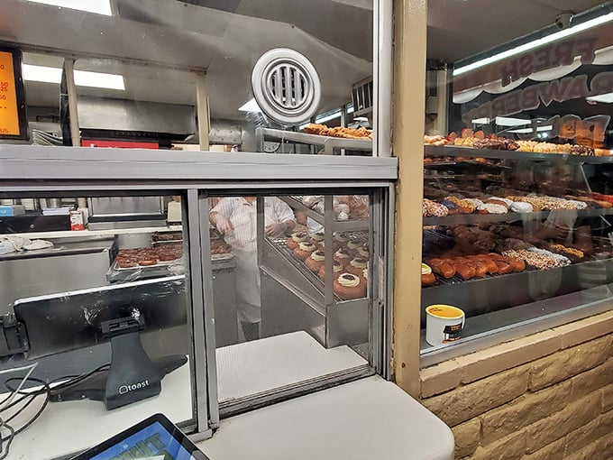 Behind these windows, donut magic happens 24/7. The display cases showcase an impressive array of freshly made treasures waiting for their forever homes.