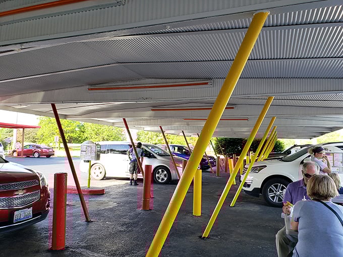 Under this canopy of nostalgia, cars gather like faithful pilgrims at a shrine to American comfort food. No apps needed—just push the button and feast.