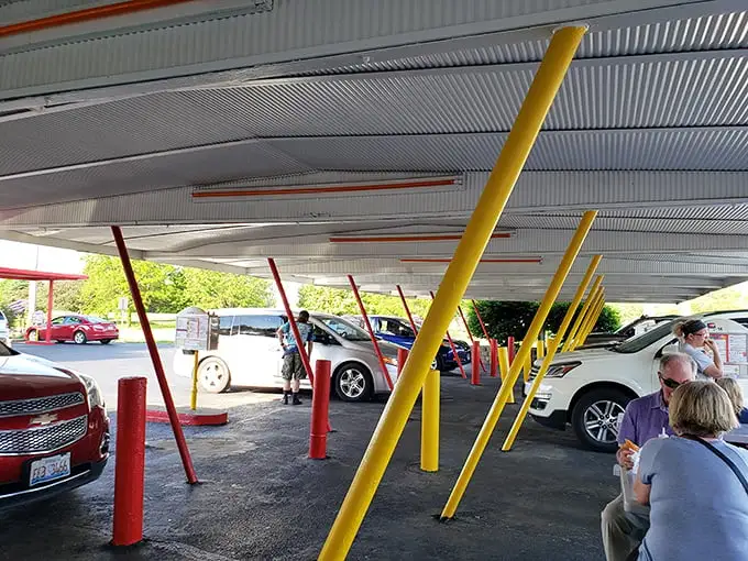 Under this canopy of nostalgia, cars gather like faithful pilgrims at a shrine to American comfort food. No apps needed—just push the button and feast.