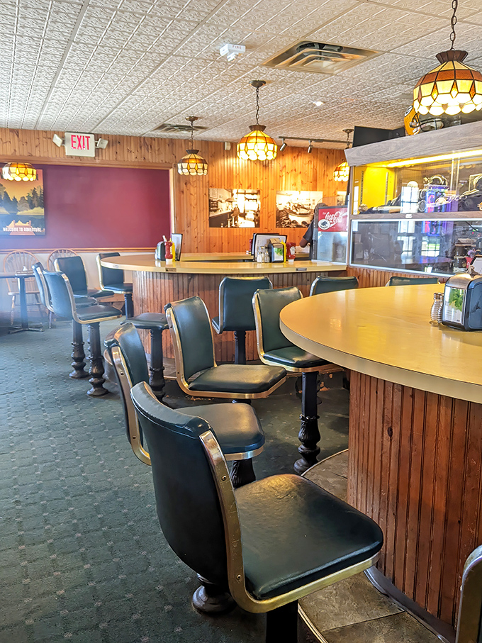 Classic diner vibes with wood paneling and vintage lighting set the stage. Those counter seats aren't just seats—they're front-row tickets to burger artistry.