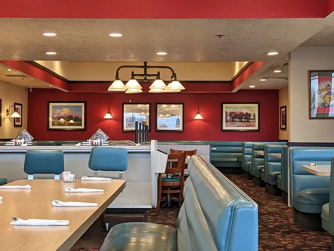 Classic diner design at its finest—where red walls, blue booths, and landscape art create the perfect backdrop for your morning philosophical debates over coffee.