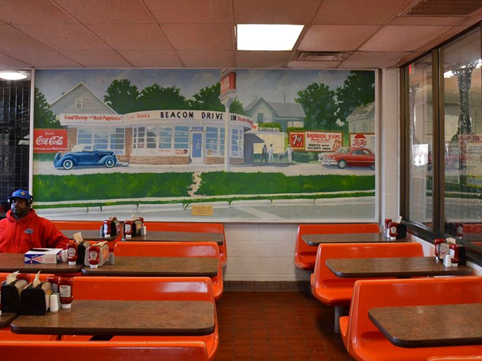 Bright orange booths frame a nostalgic mural depicting The Beacon's earlier days—a time capsule where conversations and comfort food have flowed for generations.