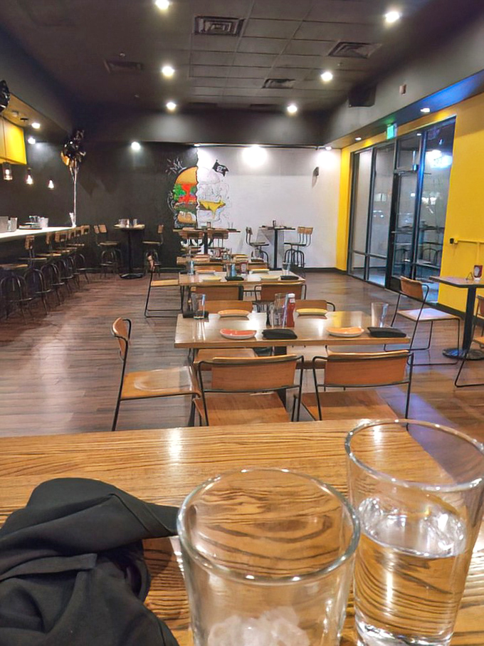 Modern minimalism meets burger paradise inside Joy Burgers, where the black and yellow color scheme sets the stage for the real stars—those magnificent patties.