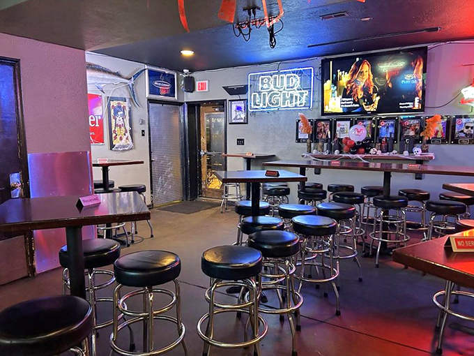 Classic bar ambiance done right—dim lighting, chrome barstools, and neon beer signs create that "I've found my new favorite spot" feeling.