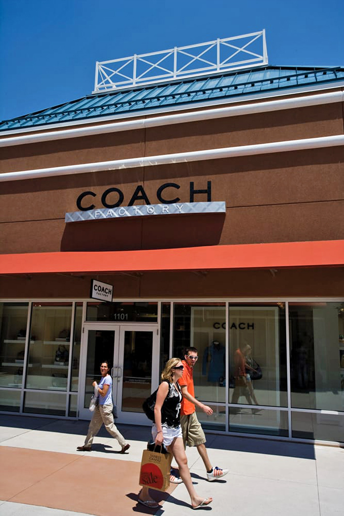The Coach mothership has landed! Shoppers emerge victorious, branded bags in hand – proof they've conquered the mountain of luxury at molehill prices.
