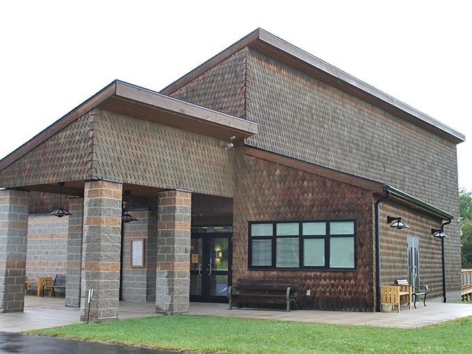 The education center's rustic architecture blends harmoniously with its surroundings, like a cozy library built by nature enthusiasts with excellent taste.