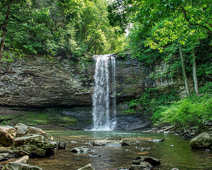 This waterfall doesn't just fall – it performs, cascading down in a perfect curtain of white against ancient stone.
