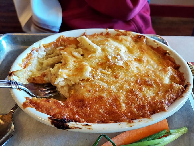 Behold the mac and cheese in all its golden glory – a bubbling cauldron of creamy perfection that makes grown adults fight over the crispy edges.