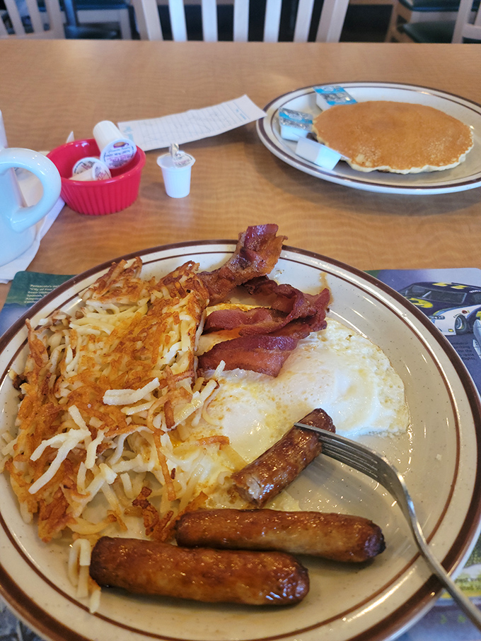 Breakfast perfection on a plate – golden hash browns with that essential crispy edge, perfectly cooked eggs, and sausage links that snap with each bite.
