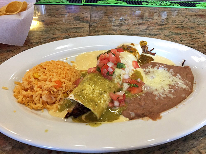 This enchilada plate isn't just dinner—it's a color wheel of Mexican flavors with green sauce, red rice, and refried beans creating edible artwork.