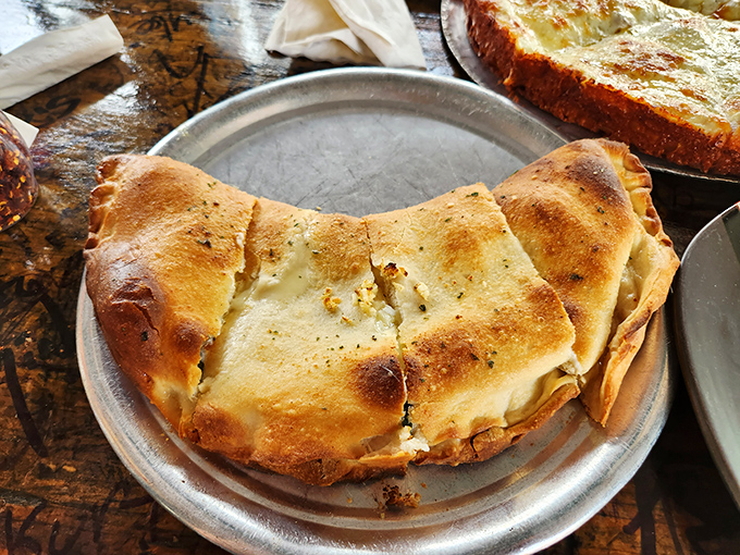This isn't just a calzone – it's a golden-brown fortress protecting a treasure trove of cheese and fillings that's worth storming the castle for.