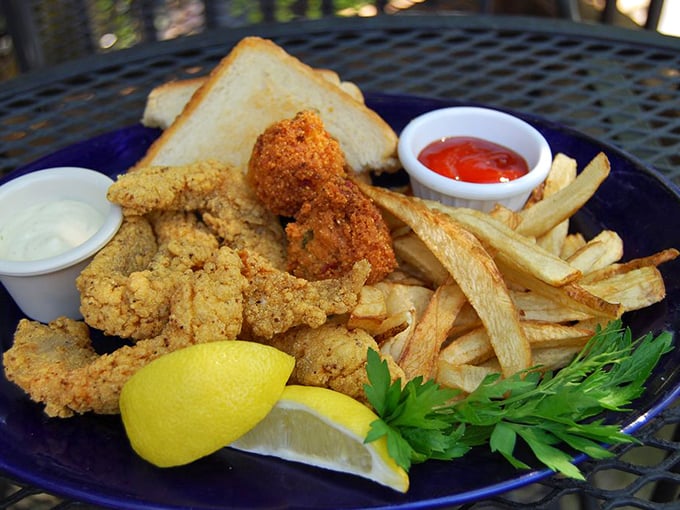 Golden-fried catfish that shatters with each bite, accompanied by crispy fries and a squeeze of lemon—simple perfection on a blue plate.