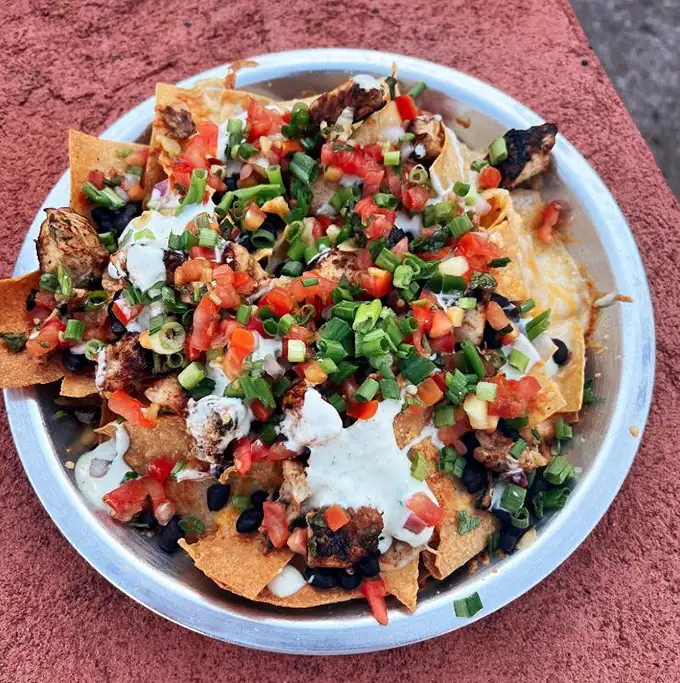 These nachos aren't just a dish—they're an architectural achievement of crispy chips, fresh toppings, and enough cheese to make Wisconsin nervous.