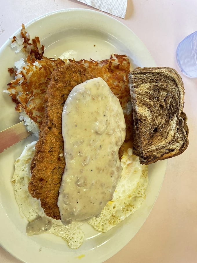 This chicken fried steak isn't just food—it's therapy on a plate, wearing a gravy overcoat and accompanied by perfect hash browns.