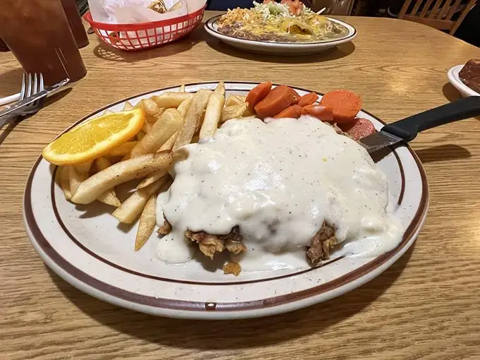 Behold, the star of our show—chicken fried steak smothered in peppery gravy with fries and veggies that know their supporting role perfectly.