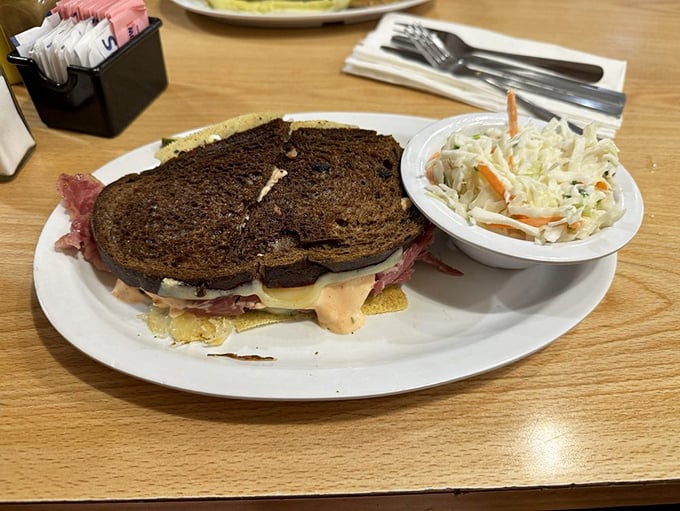 The classic Reuben arrives like a work of art – corned beef, sauerkraut, and Swiss on rye with a side of creamy coleslaw for good measure.