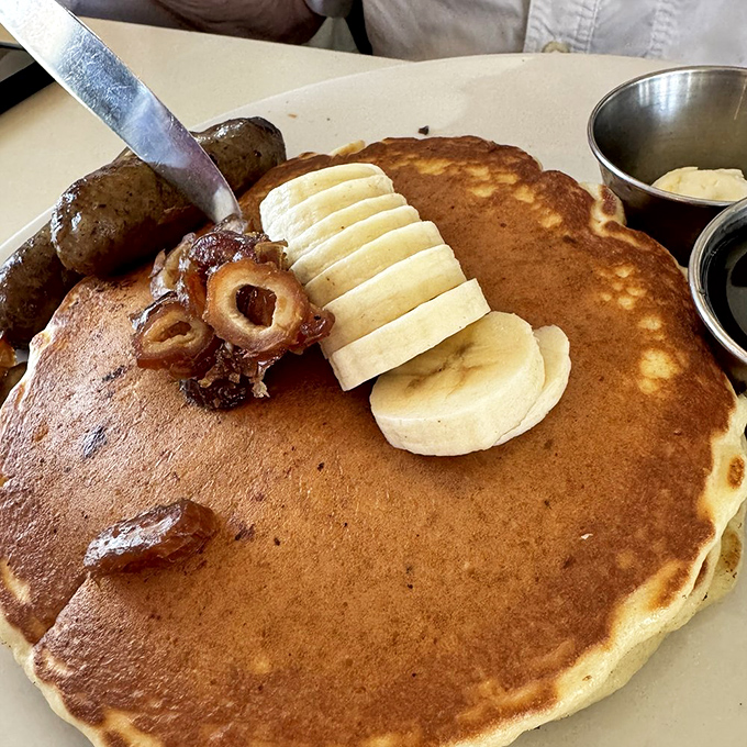 Pancake perfection with a desert twist! Golden flapjacks adorned with sliced bananas and what appears to be date pieces—breakfast elevated to art form.