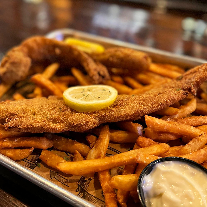 This isn't just fish and chips—it's edible architecture: a golden-battered cathedral of flavor with french fry flying buttresses and a tartar sauce baptismal font.
