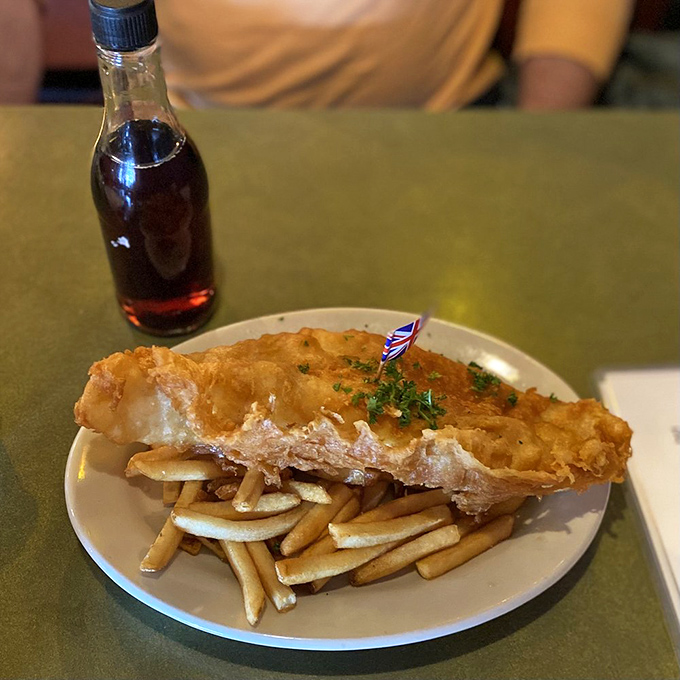 Golden, crispy batter hugging flaky white fish alongside perfectly cooked chips. That tiny Union Jack flag isn't just cute—it's a victory banner for your taste buds.
