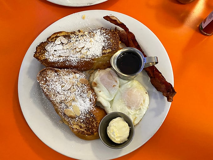 French toast so perfectly golden it could make a carb-counter weep with joy, dusted with powdered sugar and served with eggs that belong in a breakfast hall of fame.