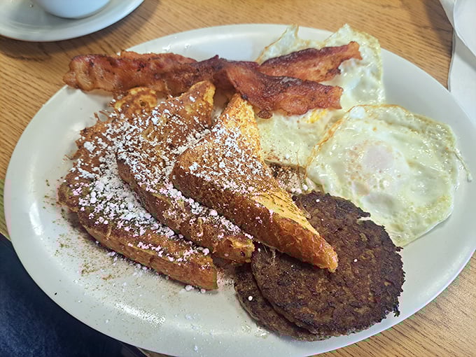 French toast that's powdered sugar perfection, eggs with just-right edges, and bacon that snaps with each bite – the breakfast holy trinity.