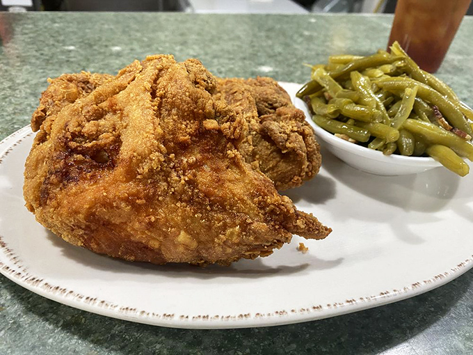 Behold the star attraction: fried chicken with a golden crust that audibly shatters with each bite, paired with perfectly cooked green beans.