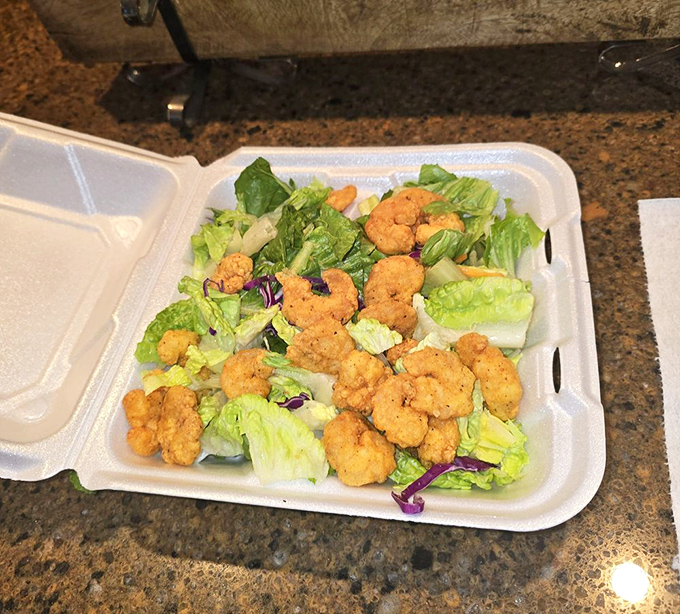 Golden fried shrimp perched atop fresh greens—proof that sometimes salads aren't just what you eat while waiting for the real food.